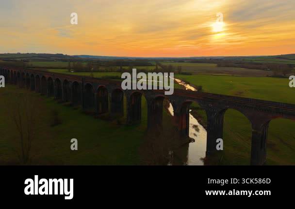 Timeless railway viaduct spanning over winding river at sunset. Viaduct ...