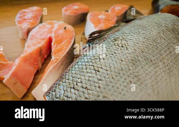 Flies crawling on whole fish and salmon steaks on wooden surface ...
