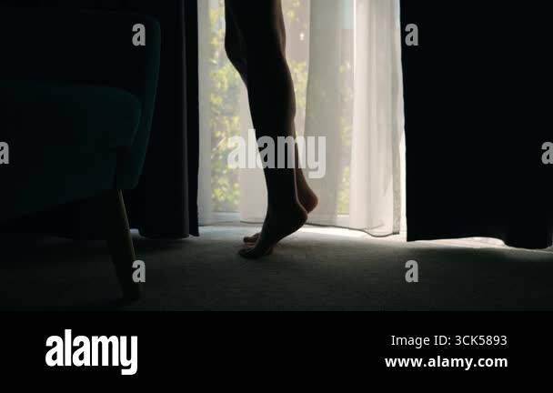 Barefoot unrecognizable slim woman standing near large window in hotel ...
