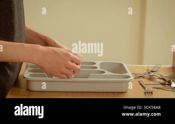 Forks placing into plastic tray. Unrecognizable person sorting cutlery ...