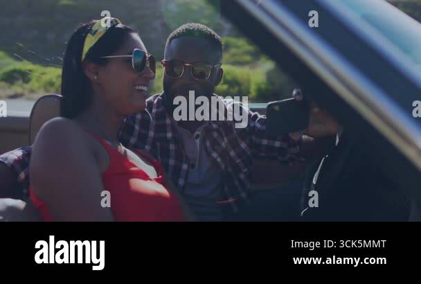 Couple recording selfie in red car, smartphone raising technology ...