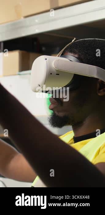 Vertical Video Black warehouse clerk uses virtual reality headset for ...
