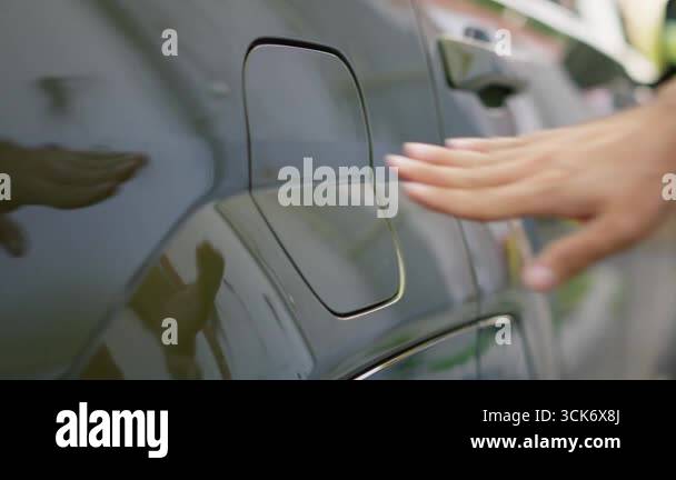 Close up of driver pushing electric car charging port flap to open it ...