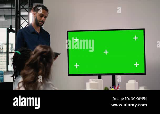 Diverse engineering staff study zoning regulations next to green screen on TV, city planning ...