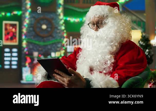 Elderly man dressed as Santa Claus looking at letter received from kids ...