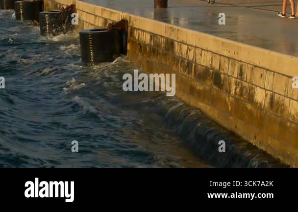 Strong sea waves crash against the old stone waterfront wall in a ...