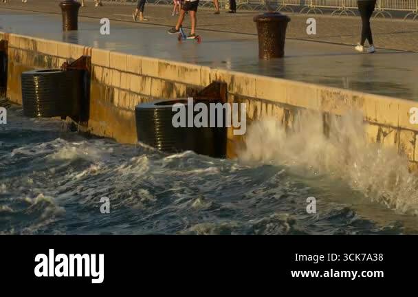 Strong sea waves crash against the old stone waterfront wall in a ...