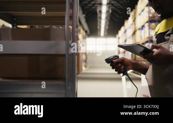 Young man using scanner on boxes barcodes tags in fulfillment center ...