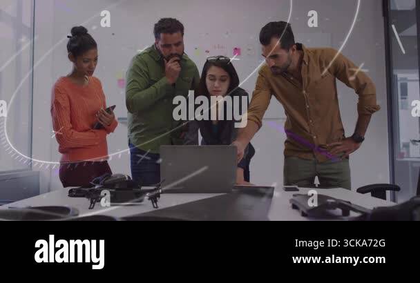 Four coworkers collaborating on drone project as woman in blazer typing design file on laptop ...