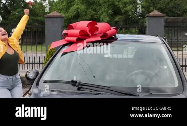 Dreams come true. Surprised woman near her new auto with big red bow ...