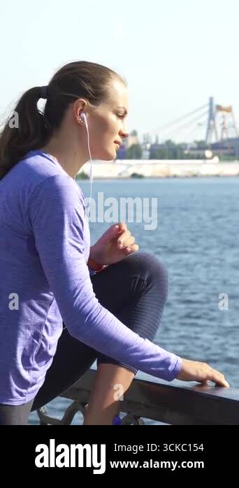A young woman with a ponytail stretches her legs on the rails ...