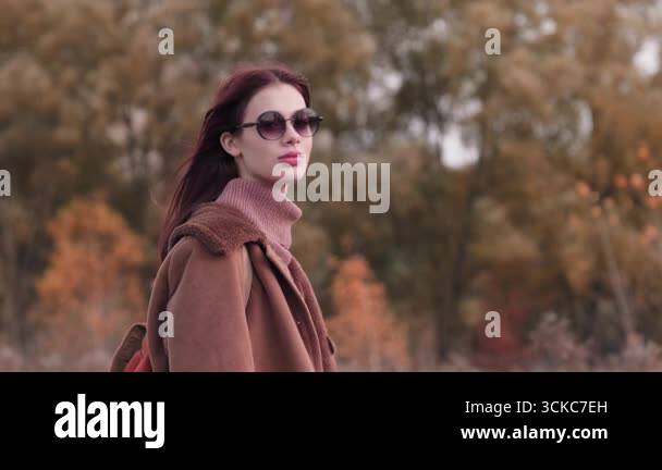 Teen girl smiling softly at the camera, dressed warmly in a brown coat ...