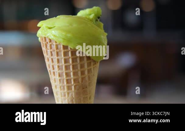 Light green pistachio ice cream in a crispy waffle cone is melting ...