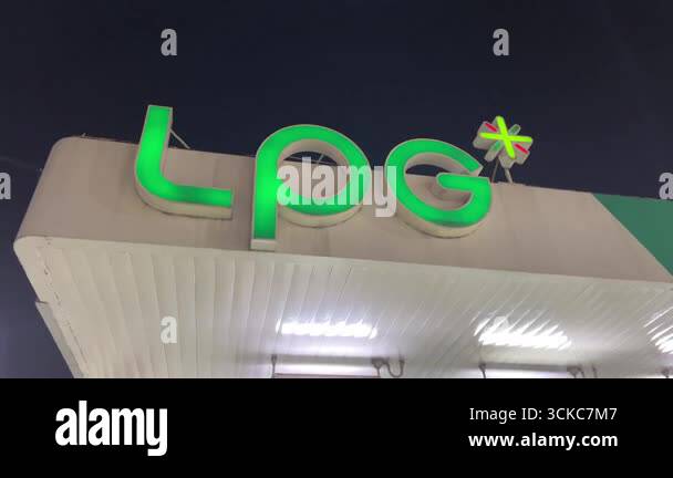 Fluorescent lights illuminate faded LPG gas station sign in green glow ...