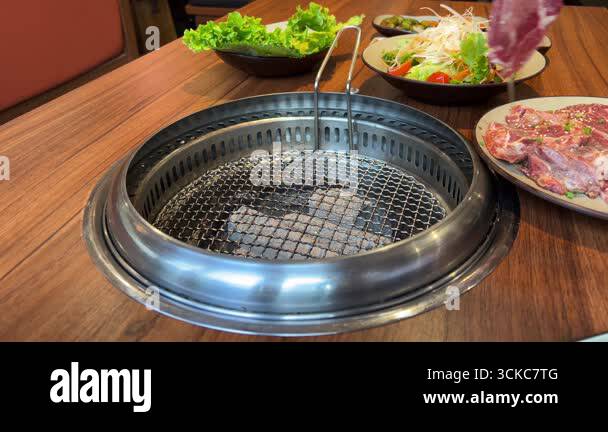 Asian Grill Restaurant Hand cooking smoked grilled pork on iron grill ...
