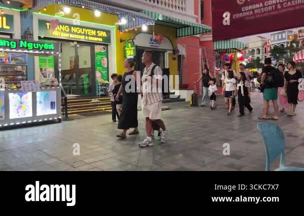 people tourists in the evening walk along the streets near the store looking at the shop windows ...