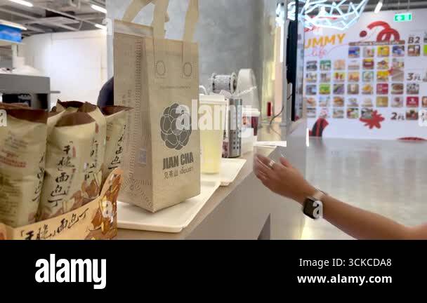 A customer buys milk tea at a modern shop in Bangkok, with bright ...