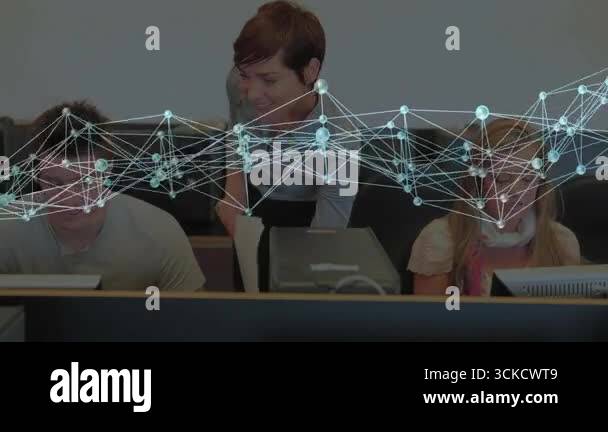 Instructor stepping behind students in computer lab, handing pages and ...