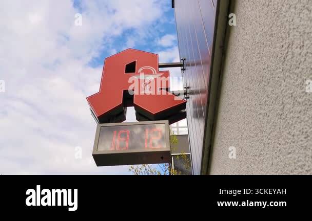 WETZLAR, GERMANY - May 02, 2019: Red pharmacy sign with digital clock ...