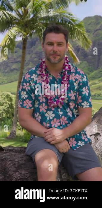 Tourist man in traditional Hawaiian shirt and flower lei relaxes under ...