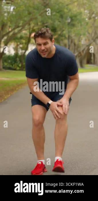 Athletic man experiences sharp knee pain mid run, grabbing his leg in ...