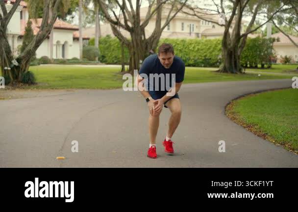 Athlete man injured while jogging in park, holding knee in pain after ...