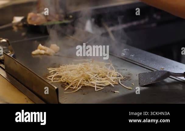 Chef cooking noodles and meat on hot grill Stock Video Footage - Alamy