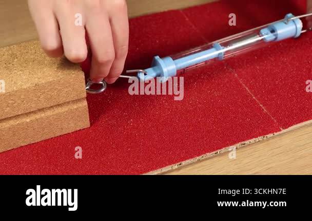 A hand uses a spring scale to measure friction on a wooden block over ...