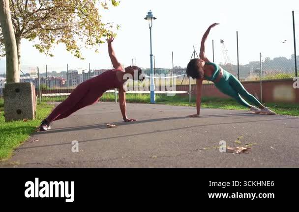 Athletic black women performing challenging side plank exercise ...