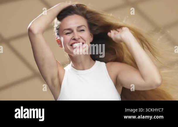 Smiling woman flipping long brown hair playfully Stock Video Footage ...