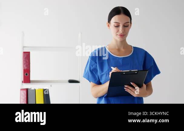 Female nurse writing notes on clipboard indoors Stock Video Footage - Alamy
