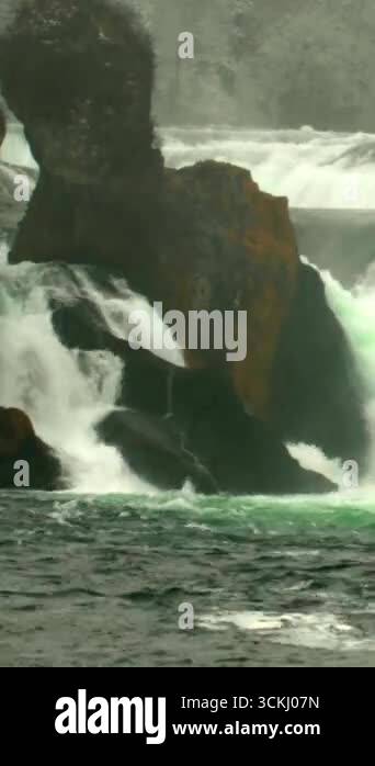 Heavy waves surge and clash against dark, jagged rocks along a stormy ...
