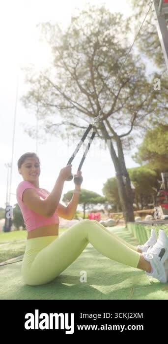 A fit woman engages in an intense outdoor workout with resistance bands ...