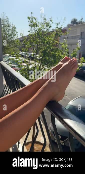 Sunkissed feet leisurely resting on a balcony railing, skillfully ...