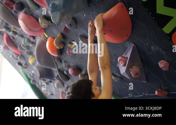 Closeup side view of a teenage boy doing pullups on a large sloper ...