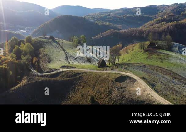Flying above autumn rural remote mountain hut with thatched roof aerial ...