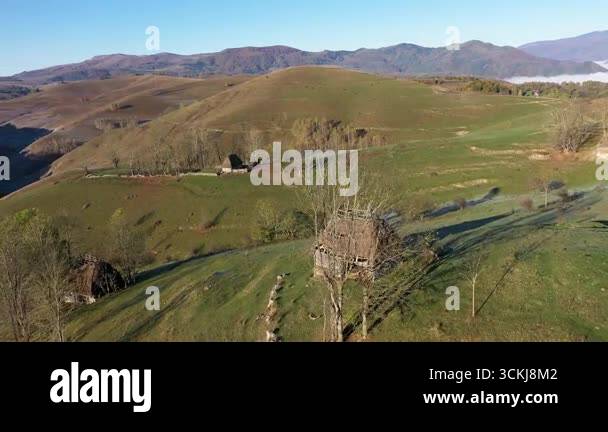 Flying above autumn rural remote mountain hut with thatched roof aerial ...