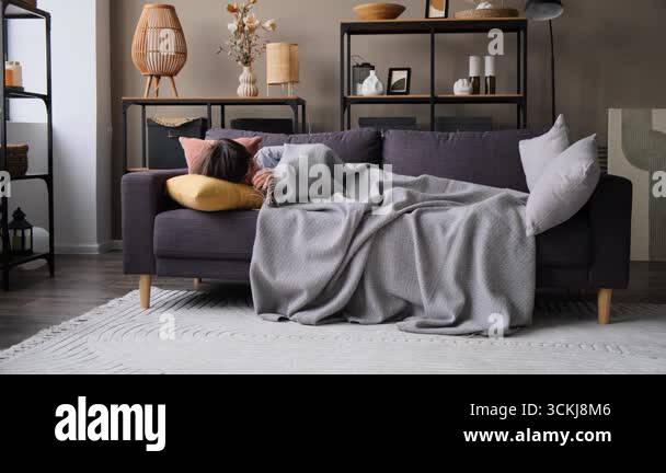 Front view of a teen boy waking up on a living room sofa, yawning and ...