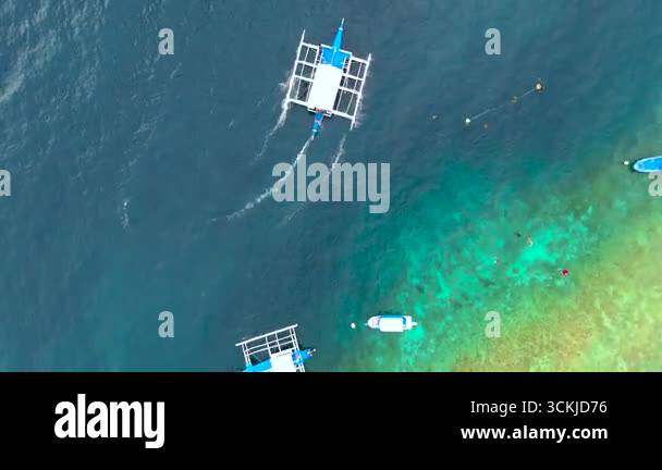 Aerial view of Filipino outrigger boats and people swimming over a ...