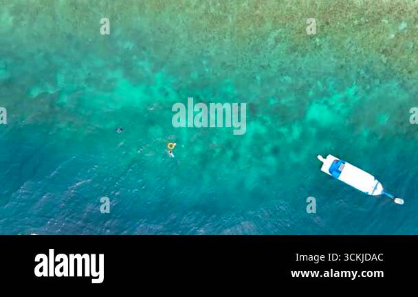 Aerial view of a white boat anchored in clear turquoise water, with two ...