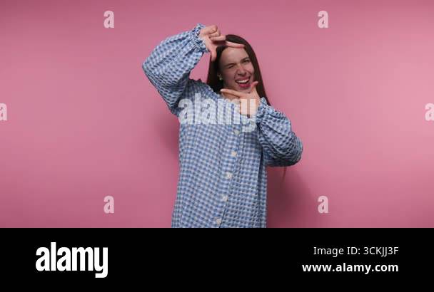 footage of young playful woman humorously poses by framing her face ...