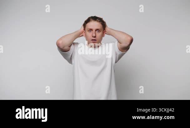 footage of young astonished man holding his face in shock, conveying a ...