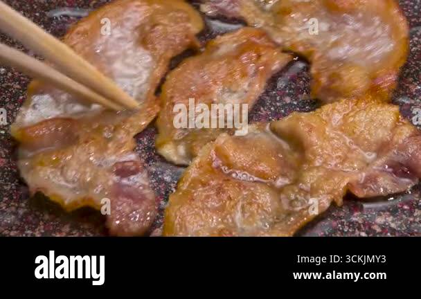 Fried Bacon Chinese Style. Thin strips of bacon are fried in bubbling ...