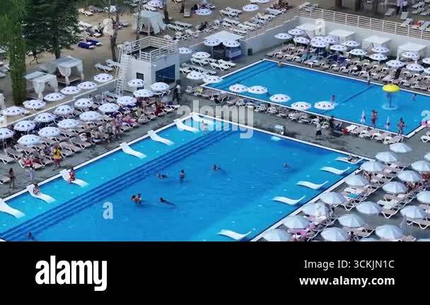 Aerial view of crowded swimming pools with people relaxing on lounge ...