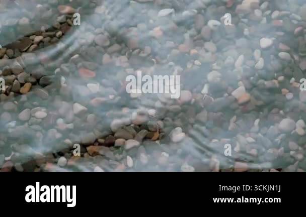 Rocky Bottom is Visible through the Water. A slight wave spreads over ...