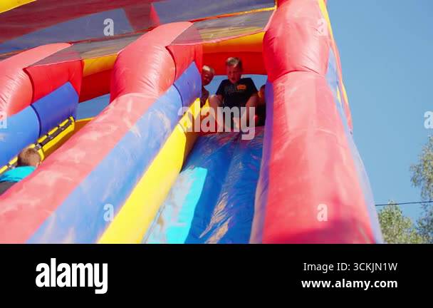 A boy slides down a colorful inflatable slide at an outdoor playground ...
