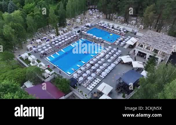 Large outdoor pool complex with many umbrellas, sunbeds and people ...