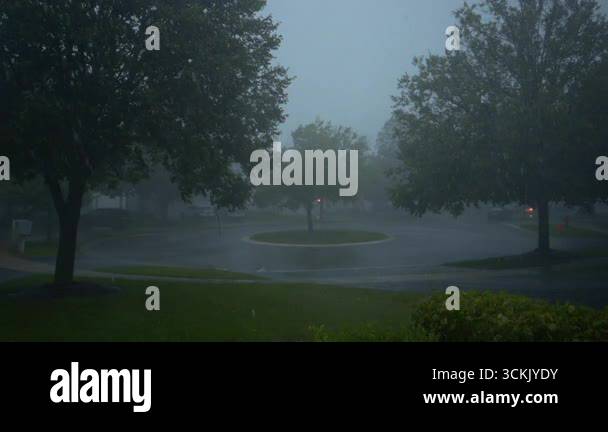 Rain falls on quiet suburban street with circle, strong wind and ...