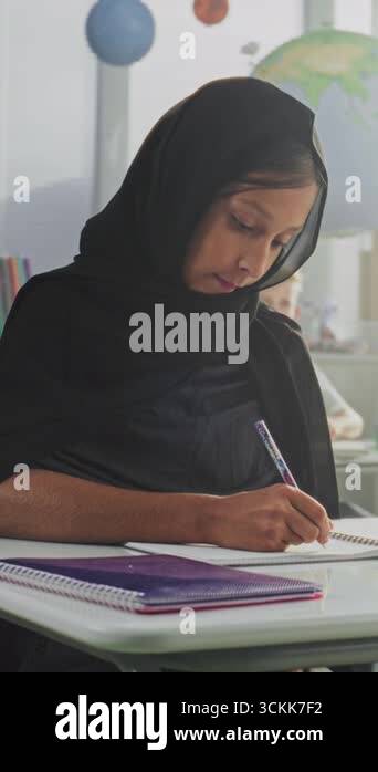 Muslim Primary School Girl Wearing Hijab Sitting at the Desk, Doing ...