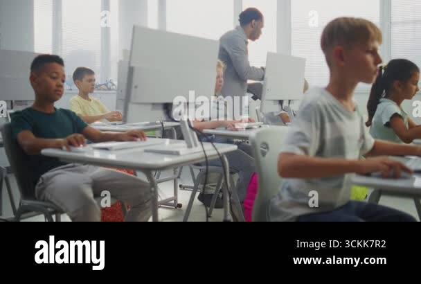 Primary School Students Working on Computers. Teacher Guiding Diverse ...